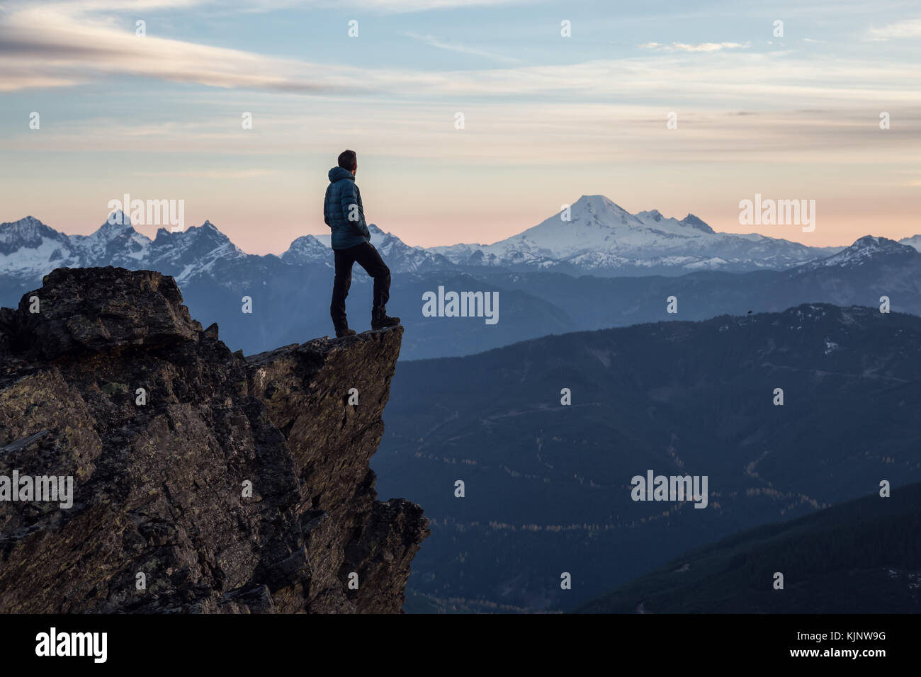 Adventurous man is standing on top of the mountain and enjoying the ...