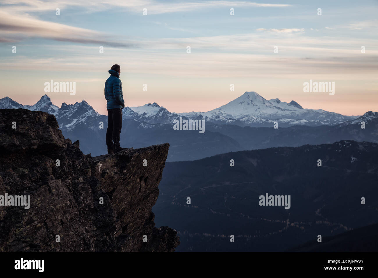 Adventurous man is standing on top of the mountain and enjoying the ...