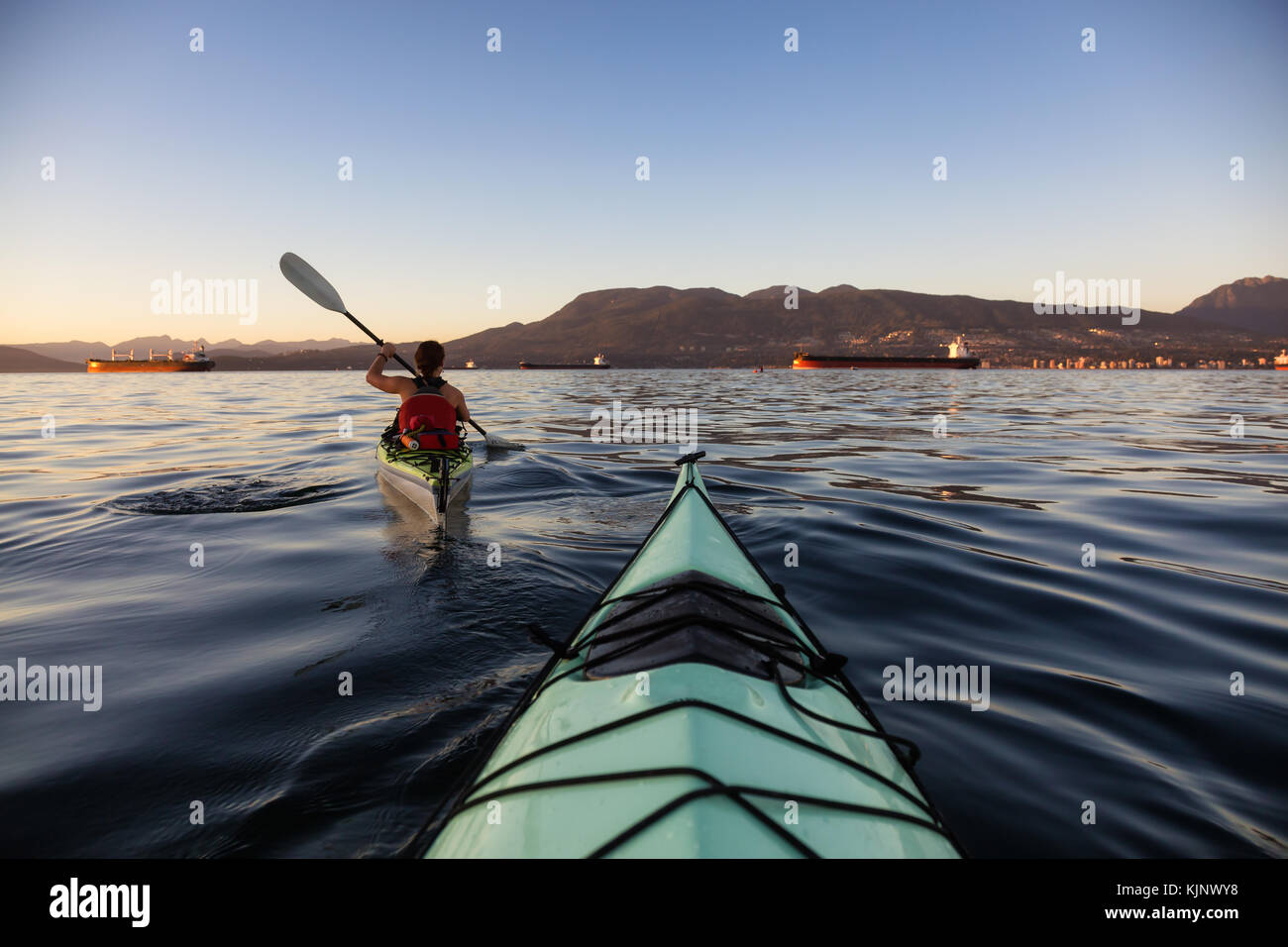 Sea kayaking in the ocean during a colorful and vibrant sunset. Taken ...