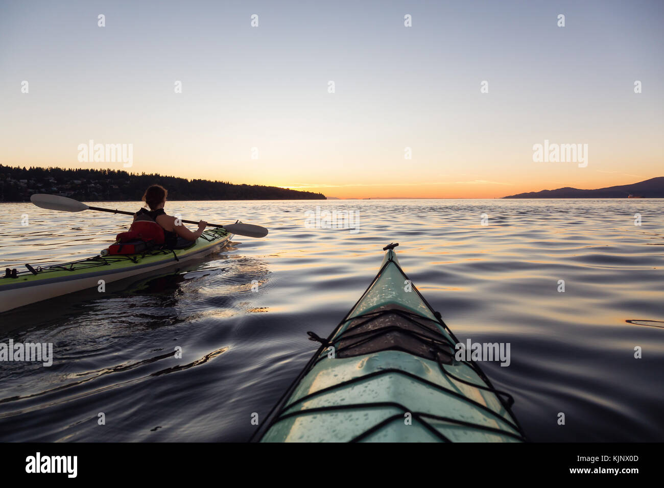 Sea kayaking in the ocean during a colorful and vibrant sunset. Taken ...