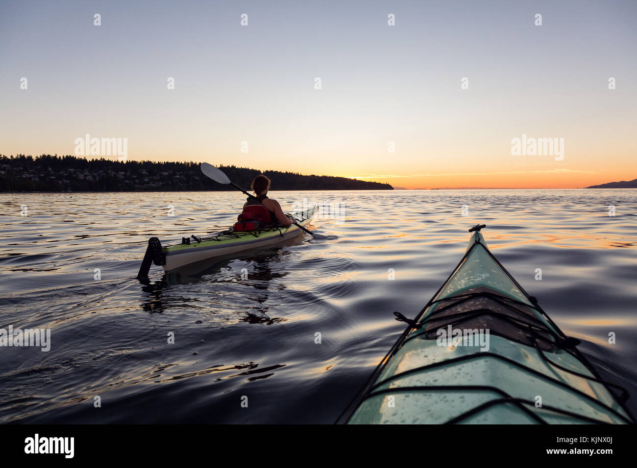 Sea kayaking in the ocean during a colorful and vibrant sunset. Taken ...