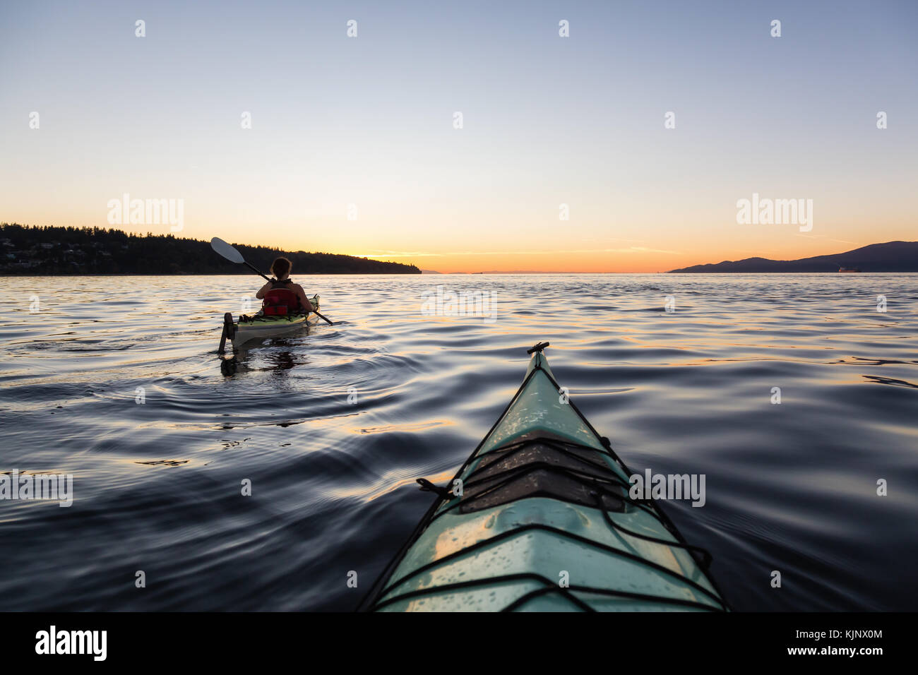 Sea kayaking in the ocean during a colorful and vibrant sunset. Taken ...