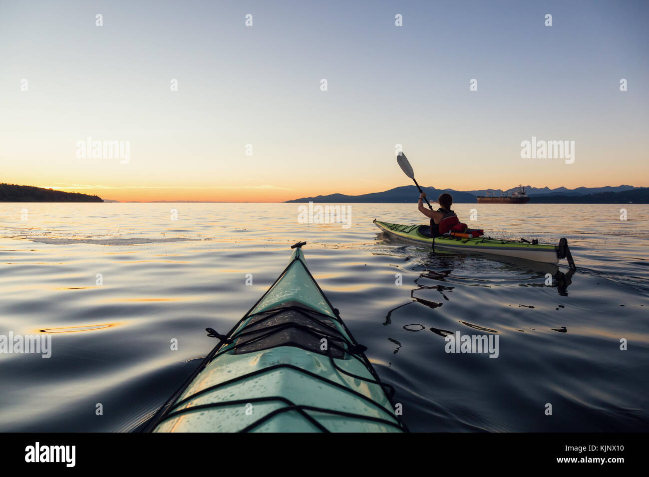 Sea kayaking in the ocean during a colorful and vibrant sunset. Taken ...