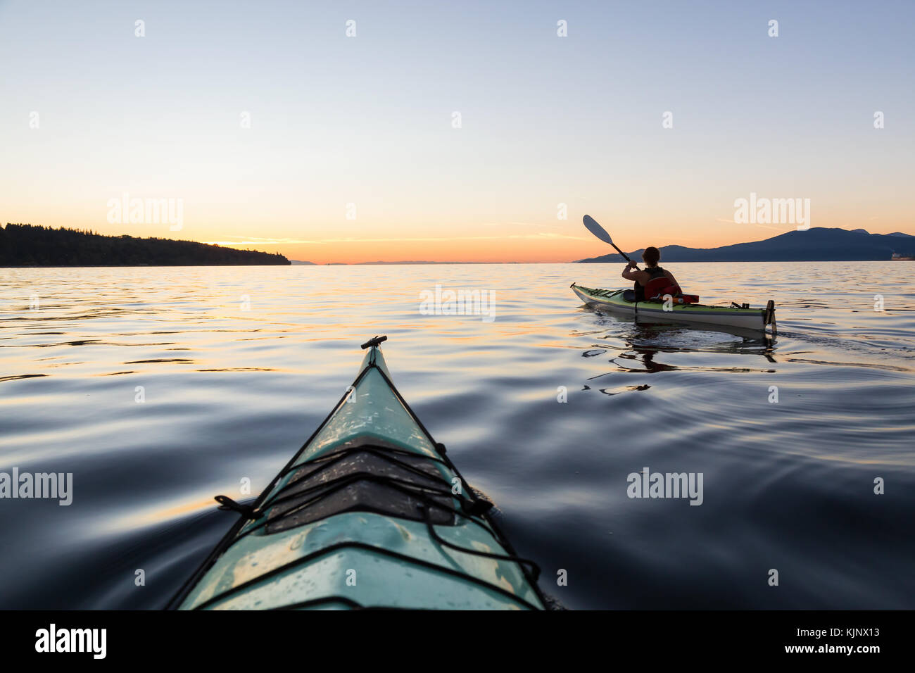 Sea kayaking in the ocean during a colorful and vibrant sunset. Taken ...