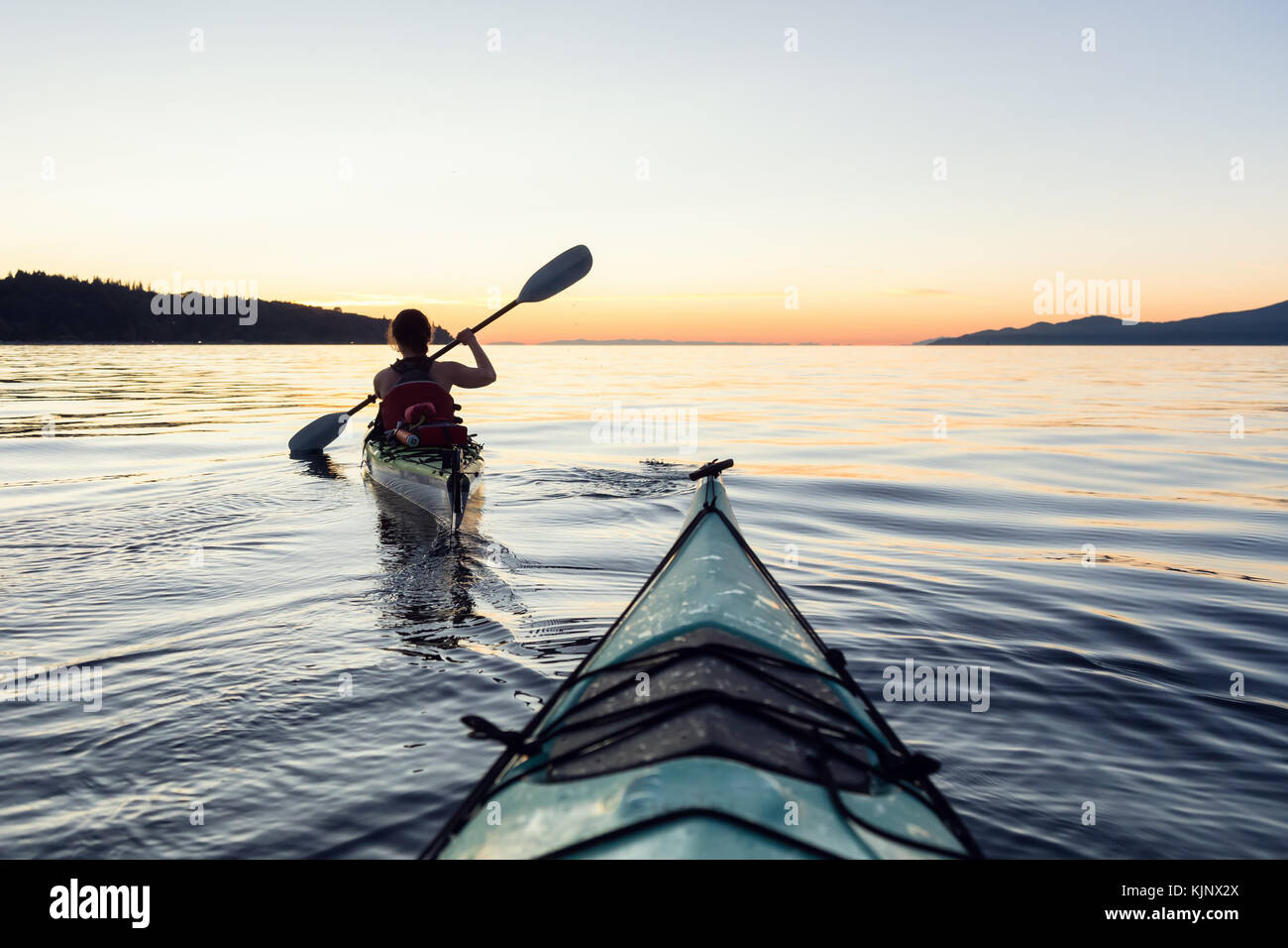 Sea kayaking in the ocean during a colorful and vibrant sunset. Taken ...