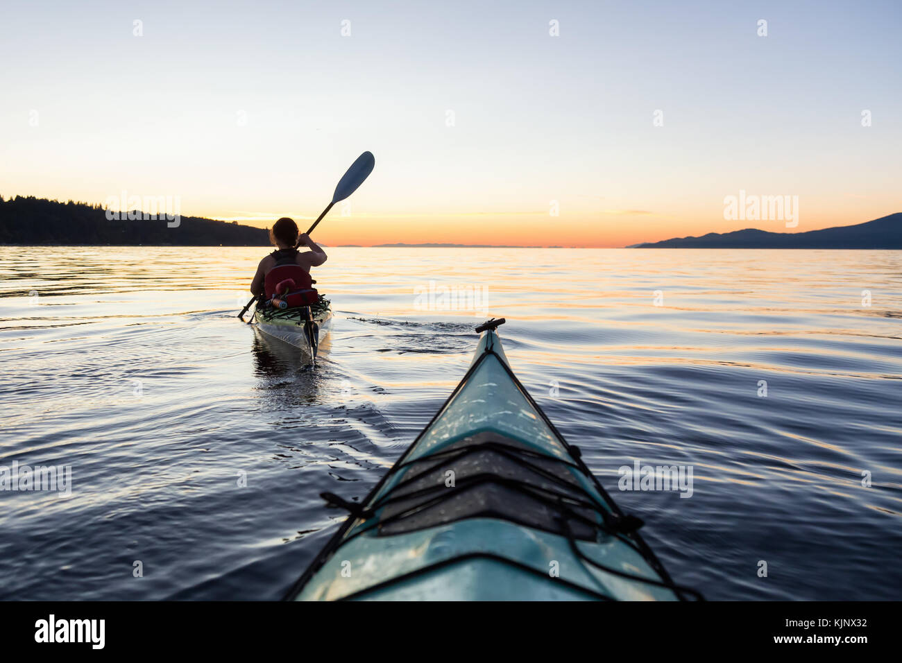 Sea kayaking in the ocean during a colorful and vibrant sunset. Taken ...