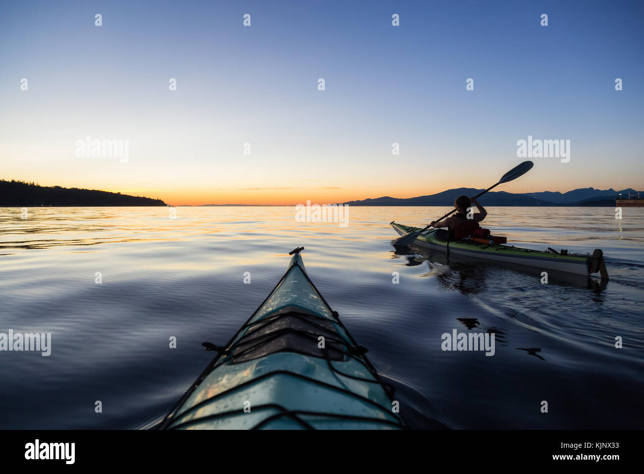 Sea kayaking in the ocean during a colorful and vibrant sunset. Taken ...