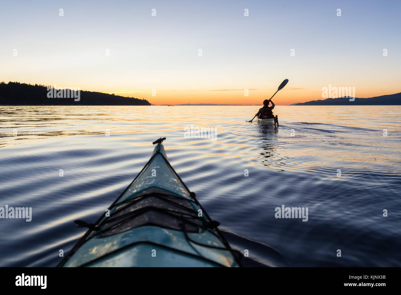 Sea kayaking in the ocean during a colorful and vibrant sunset. Taken ...