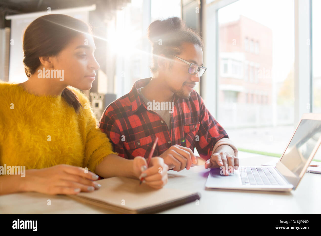 Two hispanic students preparing home assignment in front of laptop ...