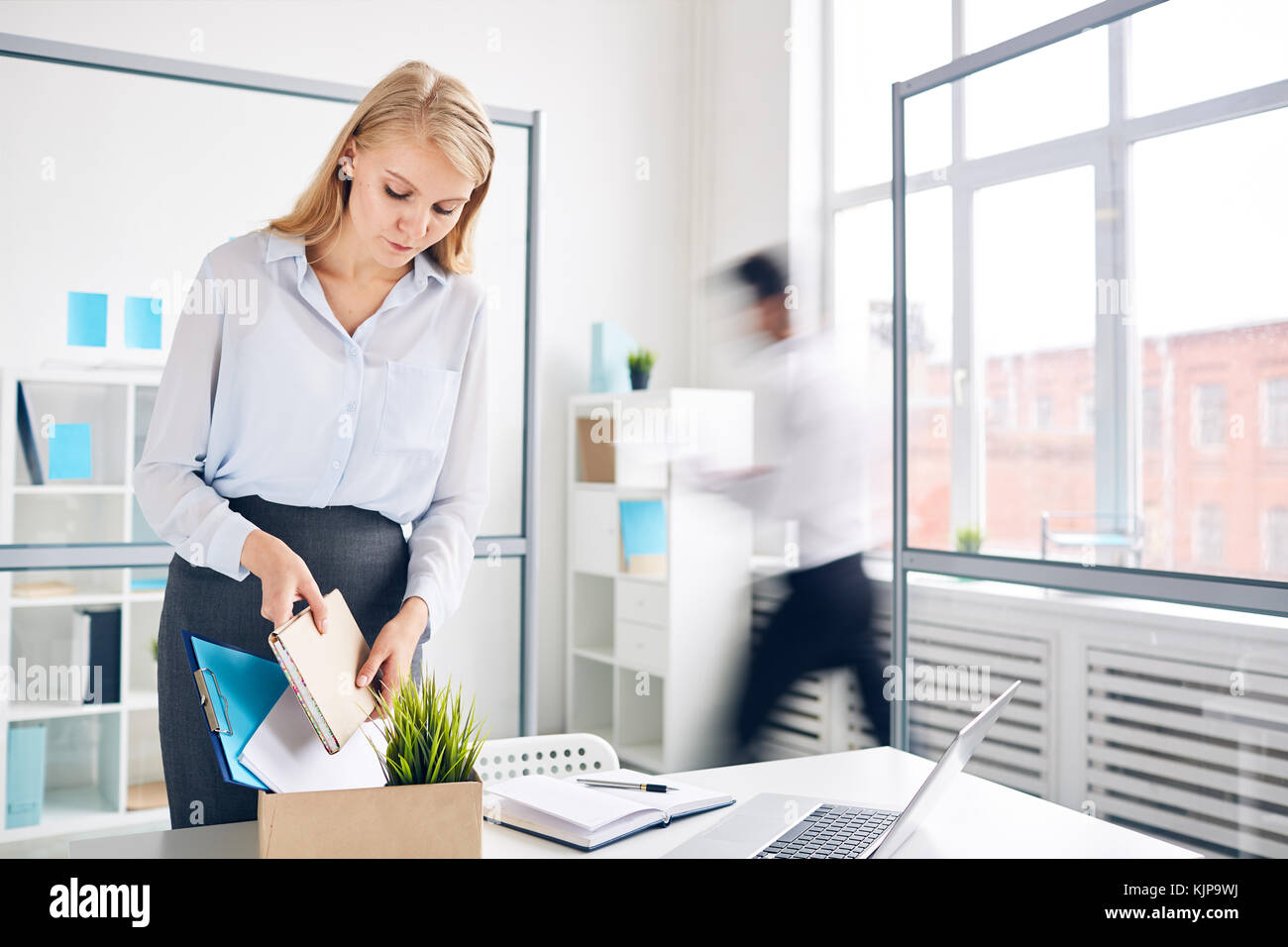 New employee taking out her things from box by workplace in office ...