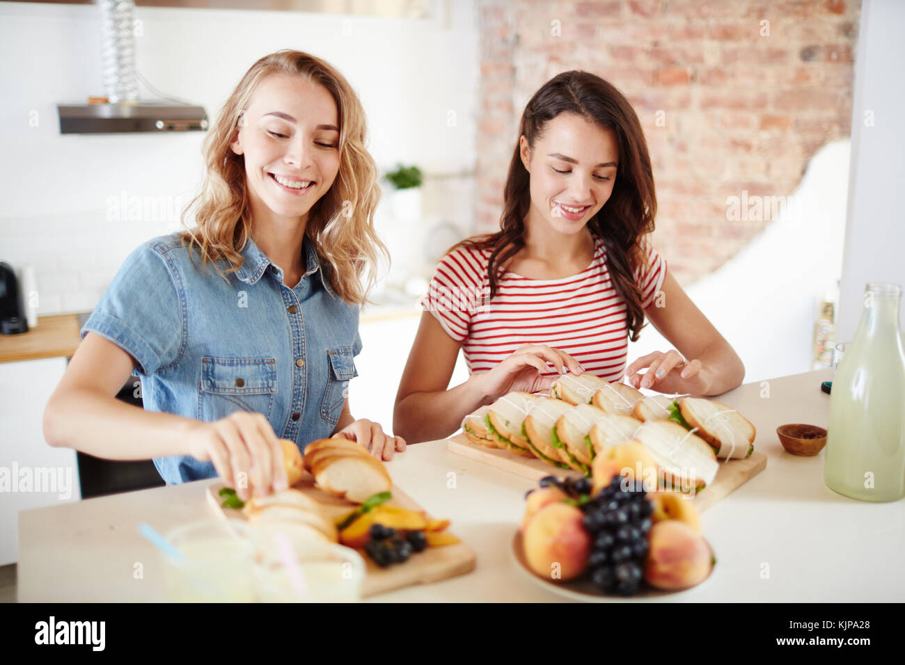 Two girls preparing sandwiches for their guests in the kitchen Stock ...