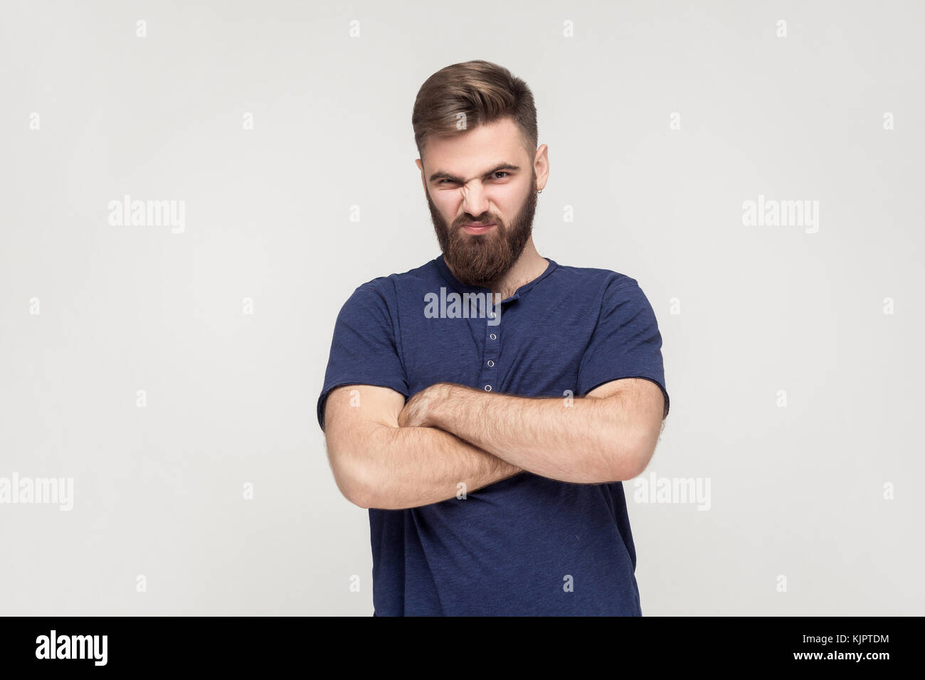 Resentful man, with arms folded, over gray background in studio shot ...