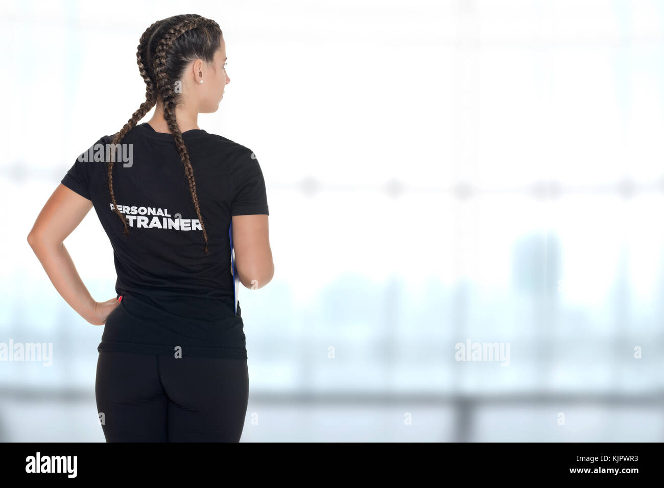 Female Personal Trainer, with his back facing the camera, in a gym ...