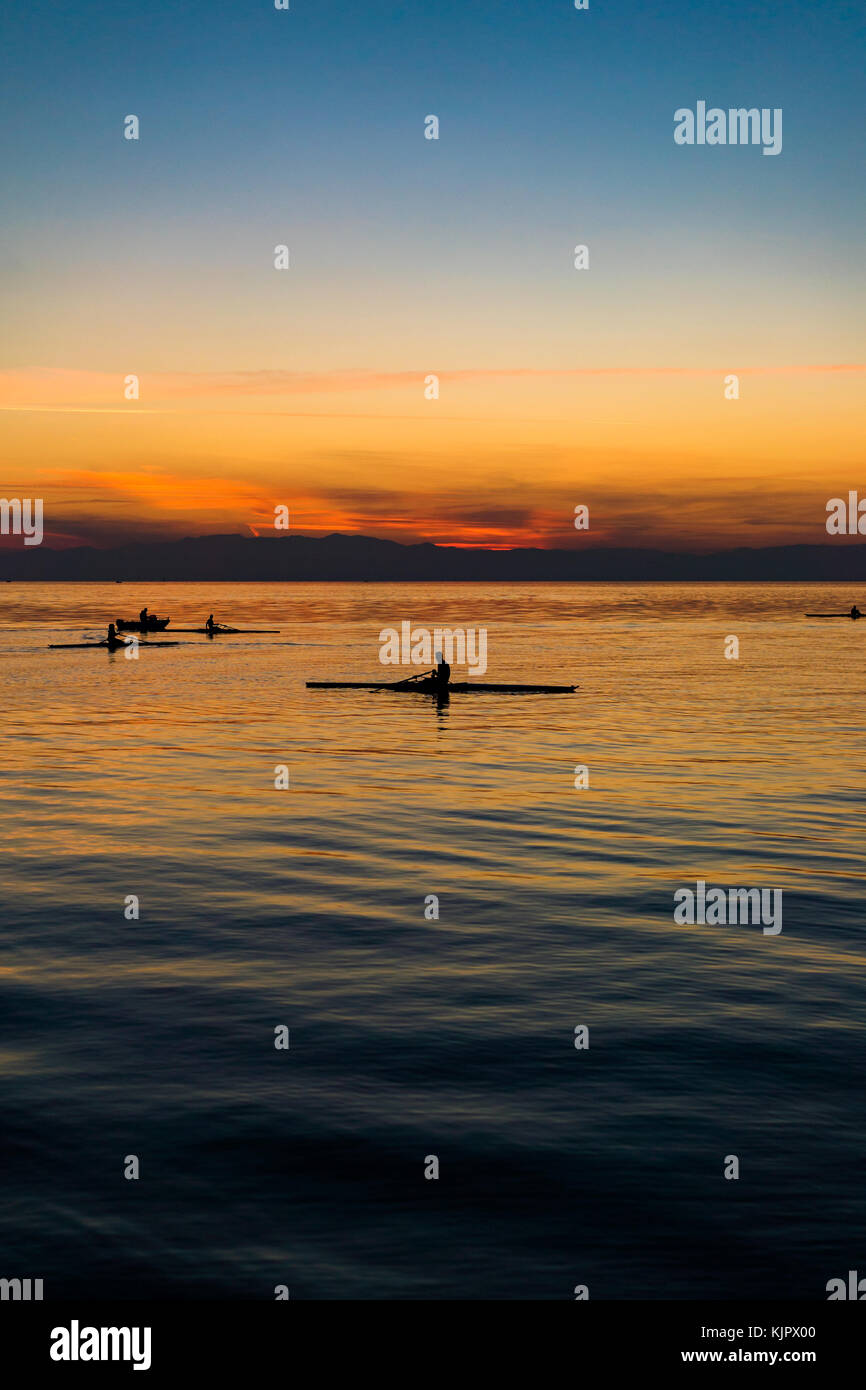 Tranquil scene of sea with rowing boats, against beautiful after sunset ...