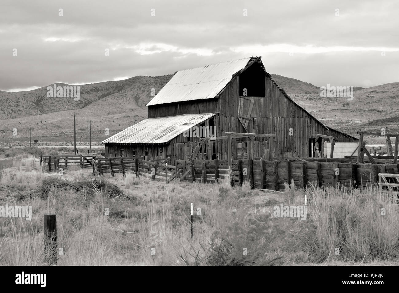 Old dilapidated wooden barn behind a wooden fence with mountains in the ...