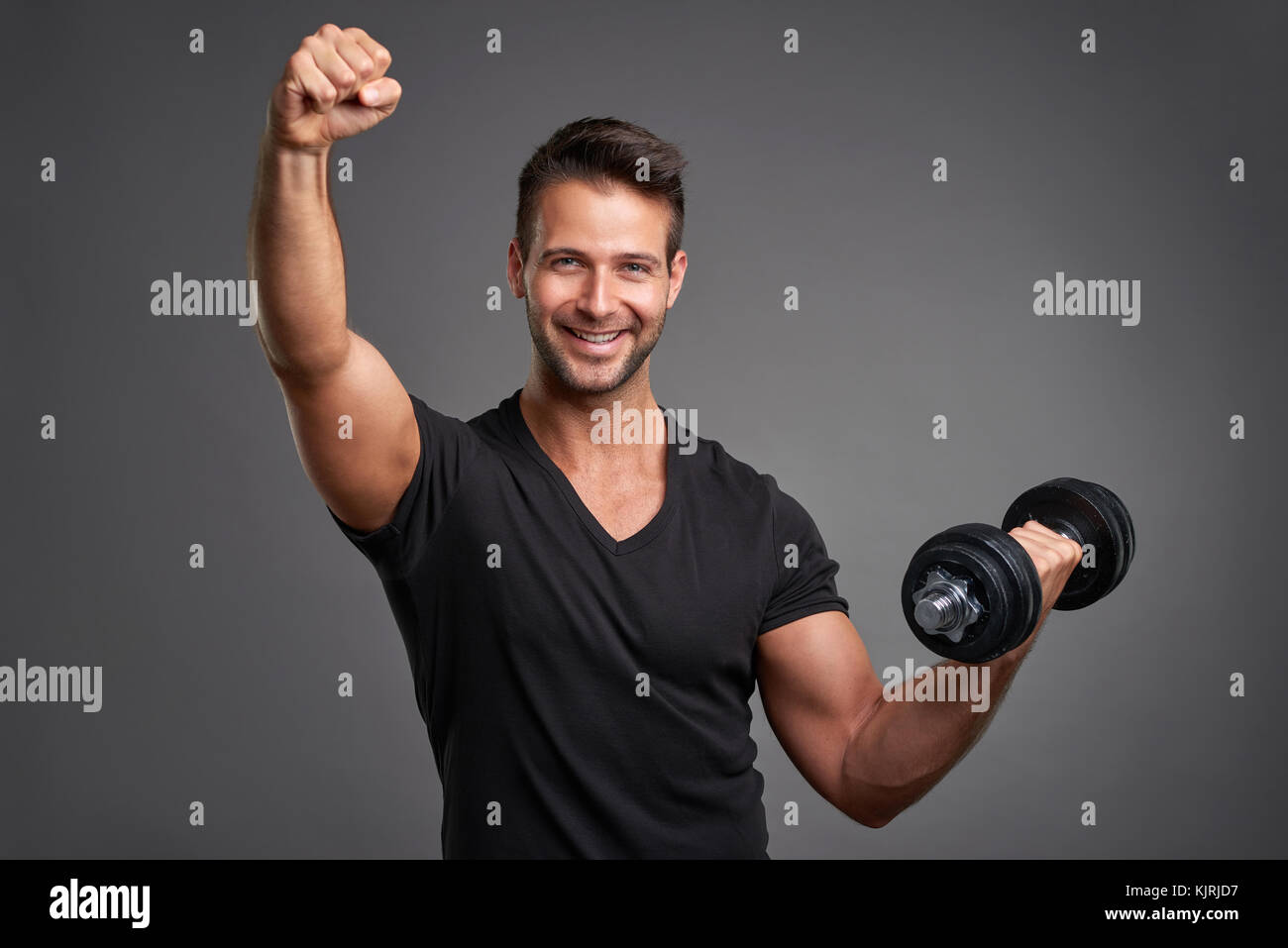 A handsome young man lifting weight smiling and raising his fist Stock ...