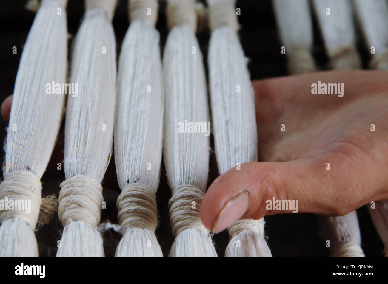 weaving and manufacturing of yarn closeup. the hand holds ready-made ...