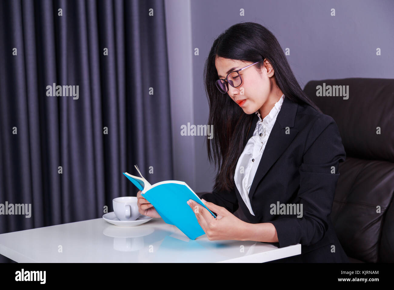 young business woman sitting at the desk and reading a book Stock Photo ...