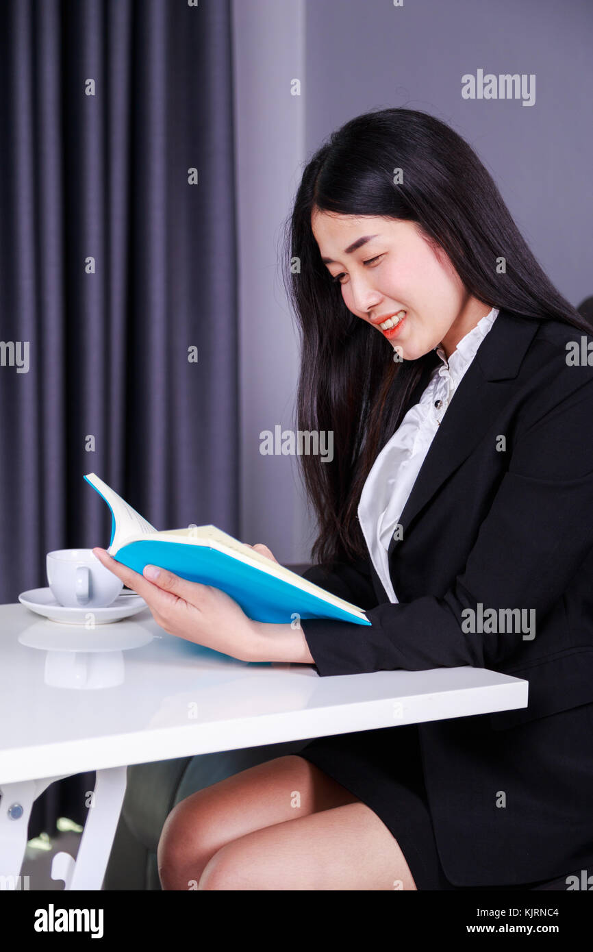happy business woman sitting at the desk and reading a book Stock Photo ...