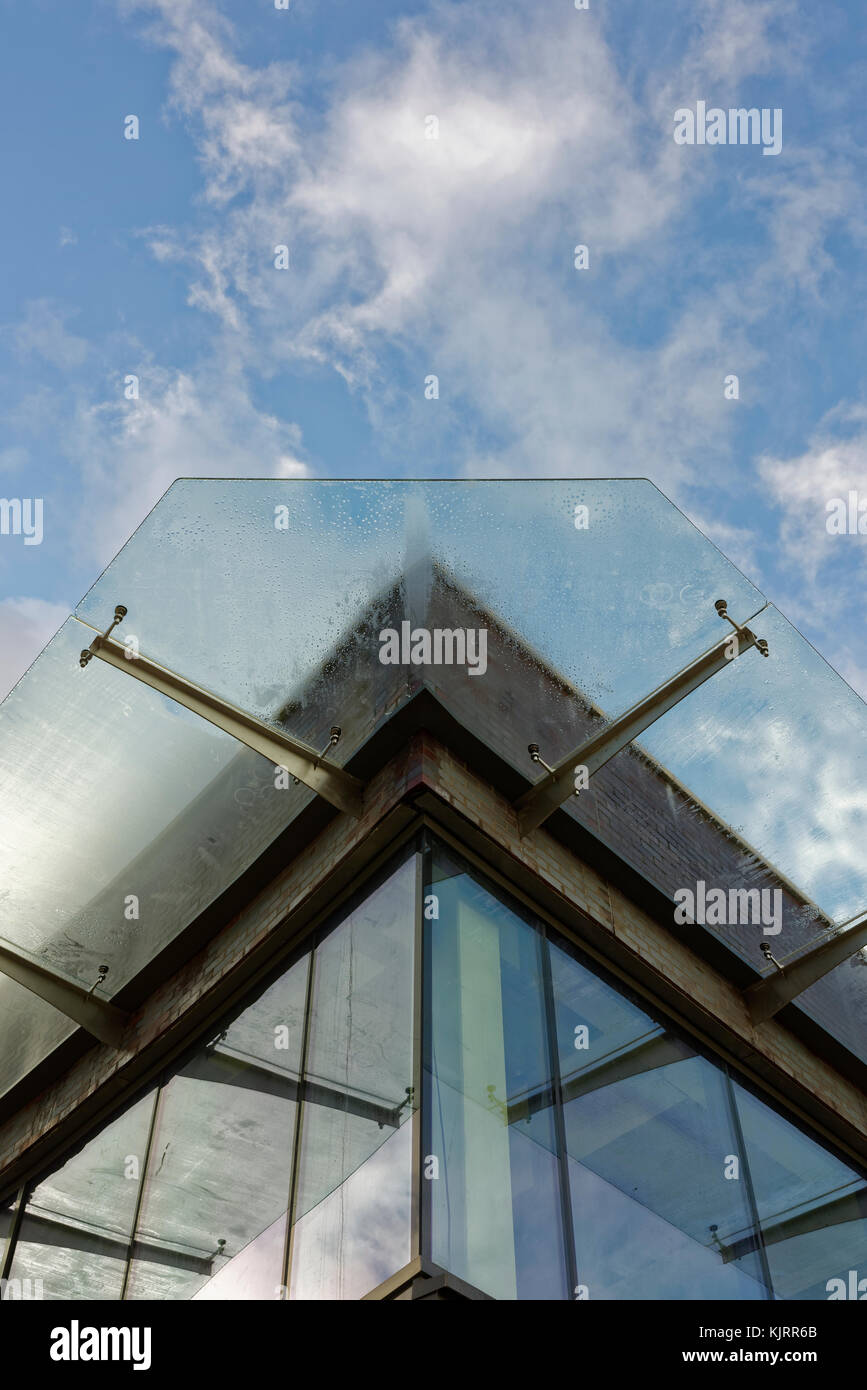Glass canopy suspended on stainless steel brackets above glass curtain ...