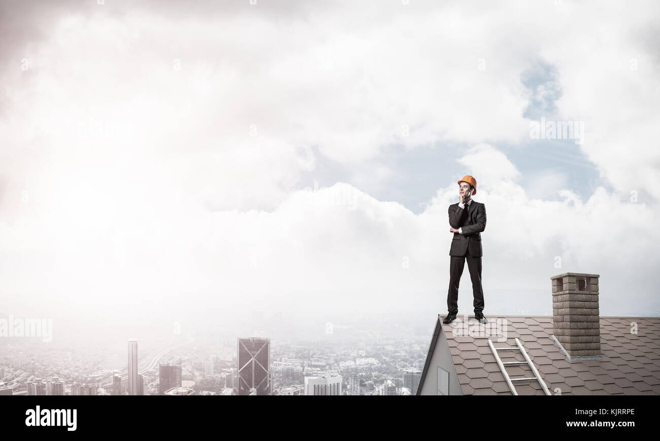 Engineer man standing on roof and looking away. Mixed media Stock Photo ...