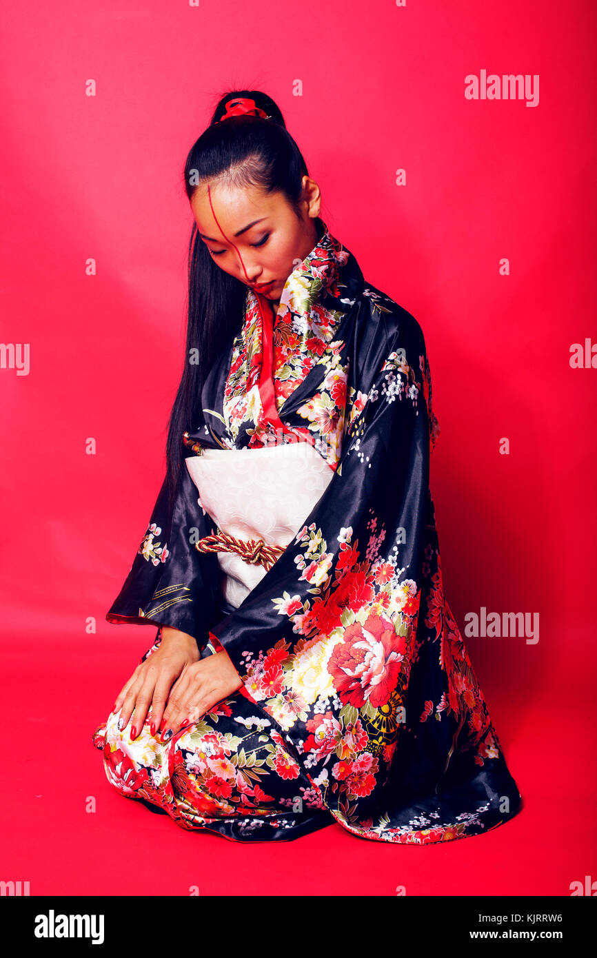 young pretty geisha on red background posing in kimono, oriental people ...