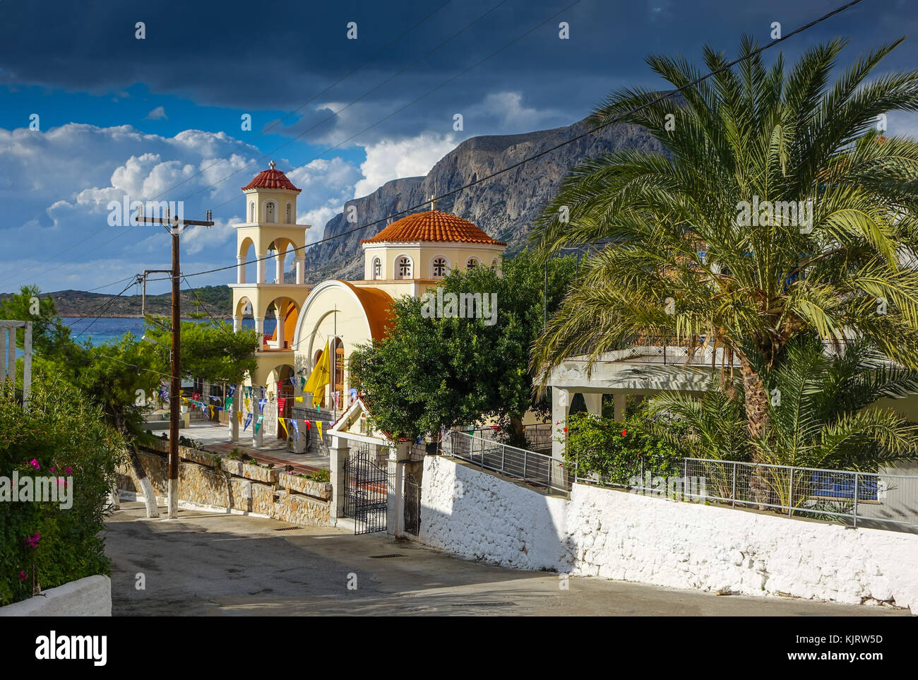 Greek orthodox church with palm tree and cumulus clouds, Kalymnos ...