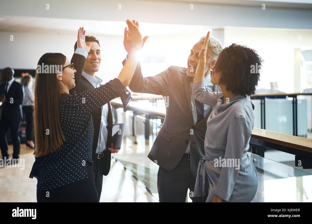 Diverse group of smiling businesspeople high fiving each other while ...