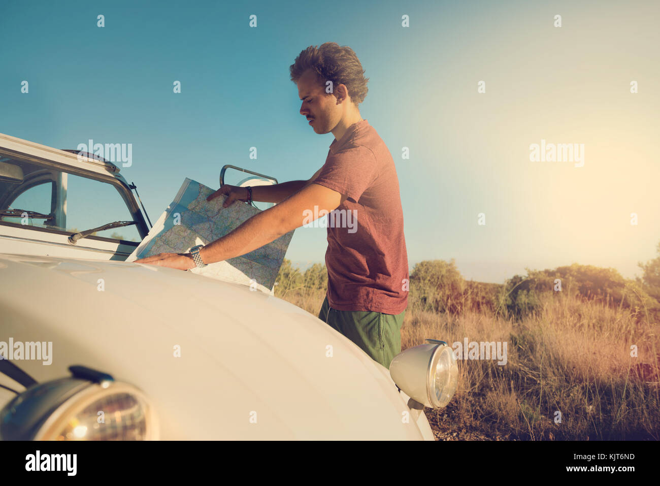 Vintage style image of a man looking at a map over a car in countryside ...
