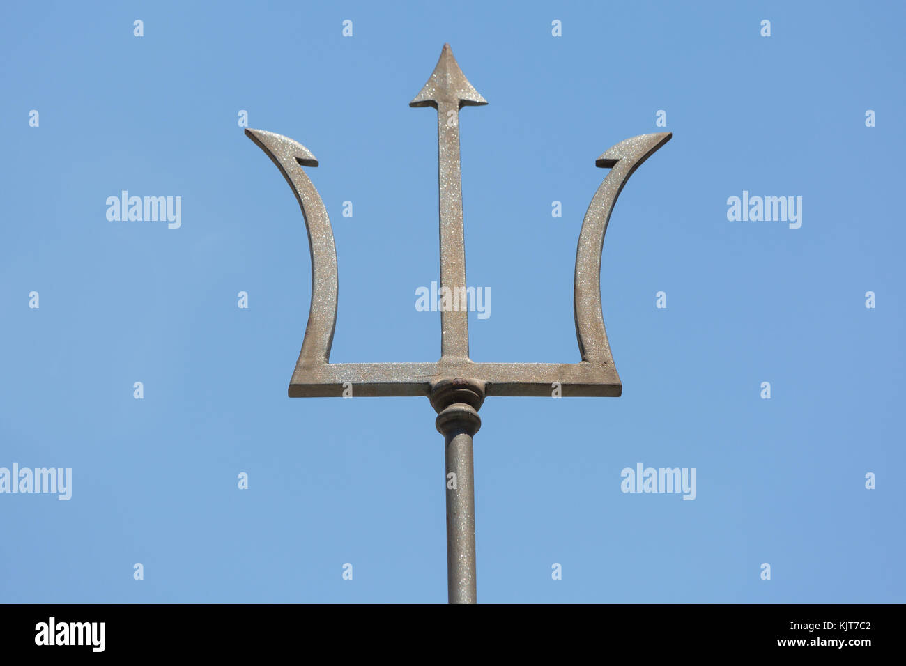 Top of an old metal trident of a neptune statue on blue sky in Triest ...