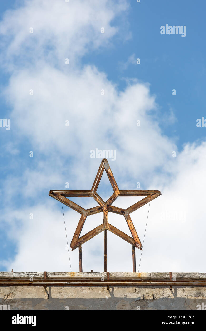 Ruined rusty metal star with broken neon lights on top of a building in ...