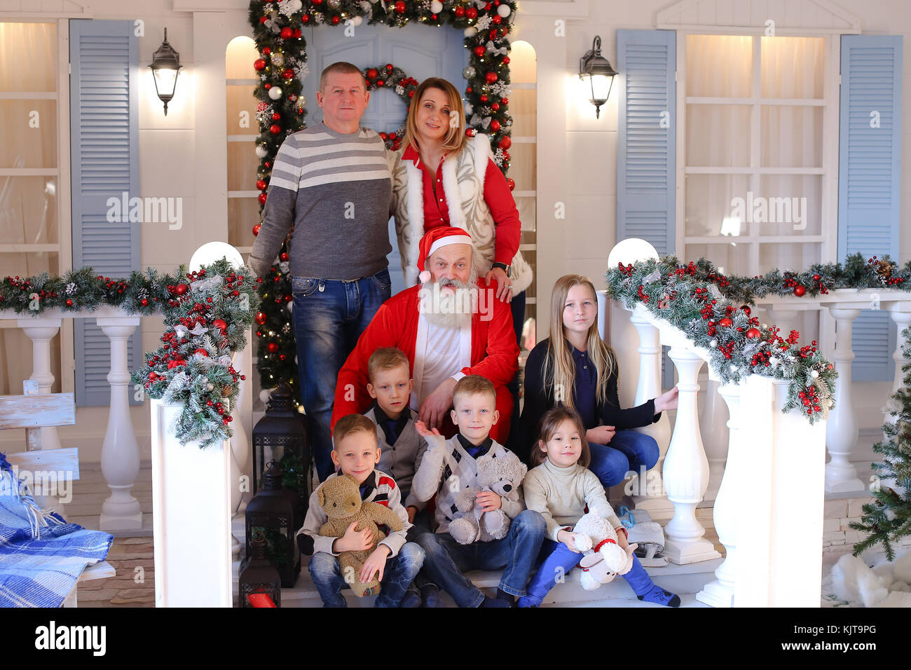 Friendly family and Santa Claus posing for camera on porch of ho Stock ...