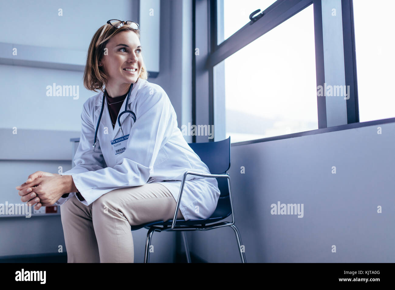 Portrait of female medical professional sitting on chair in hospital ...