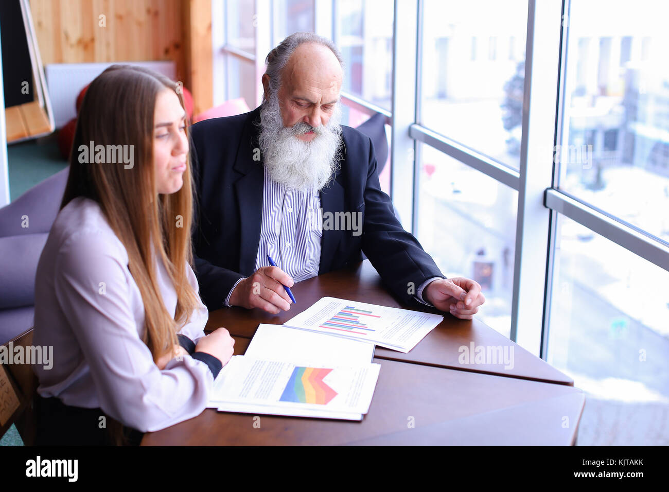 Elderly boss man signs document with young assistant with papers Stock ...