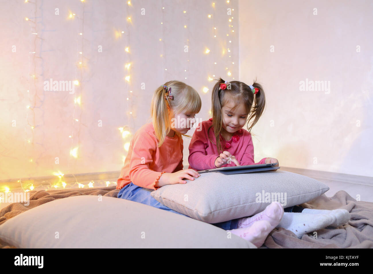 Little girls involved in use of tablet and sit on floor in brigh Stock ...