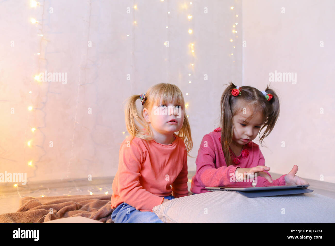 Little girls involved in use of tablet and sit on floor in brigh Stock ...