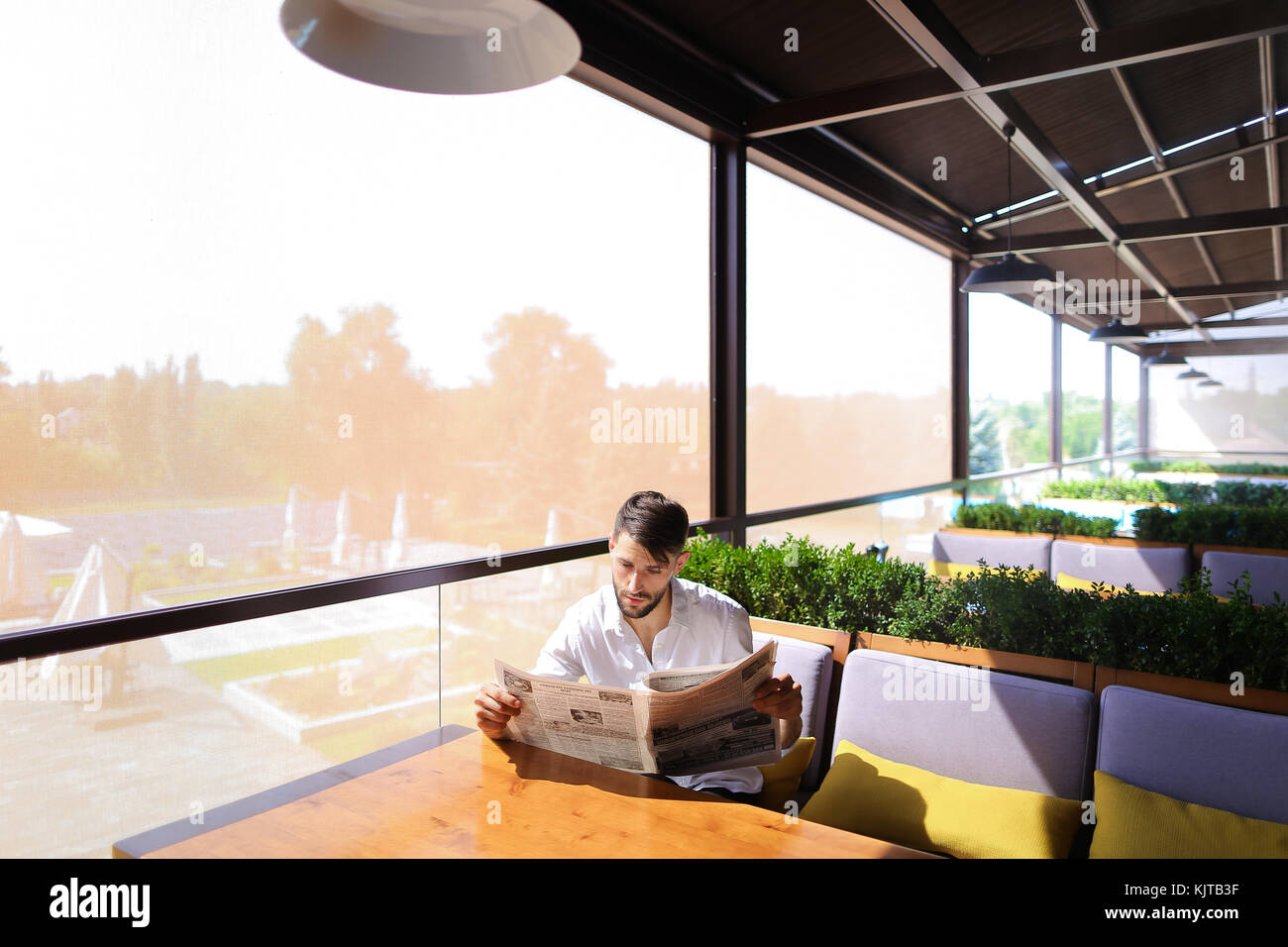 Handsome male person reading newspaper and wondering Stock Photo - Alamy