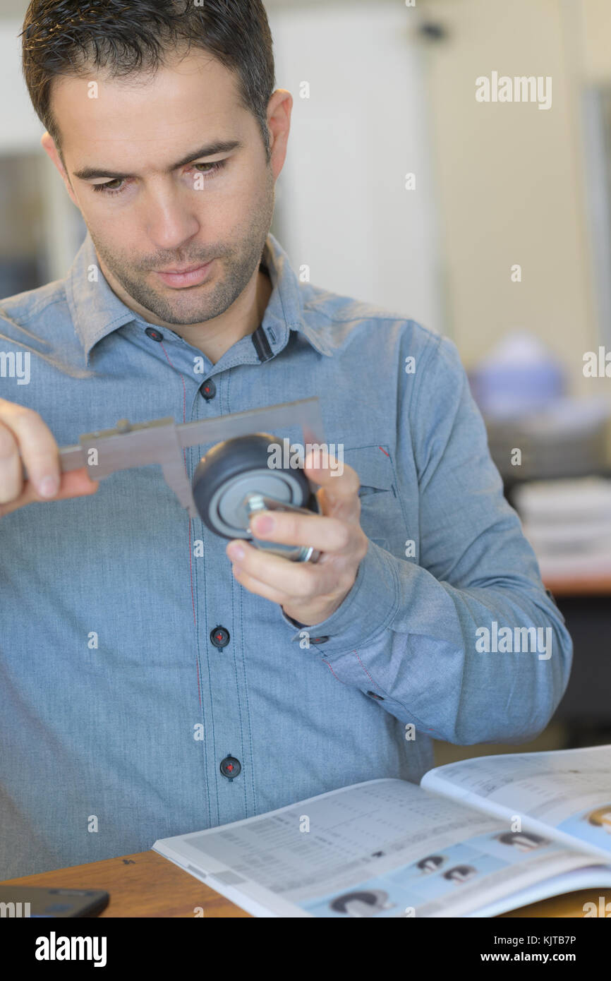 man using calipers to measure small wheel Stock Photo - Alamy