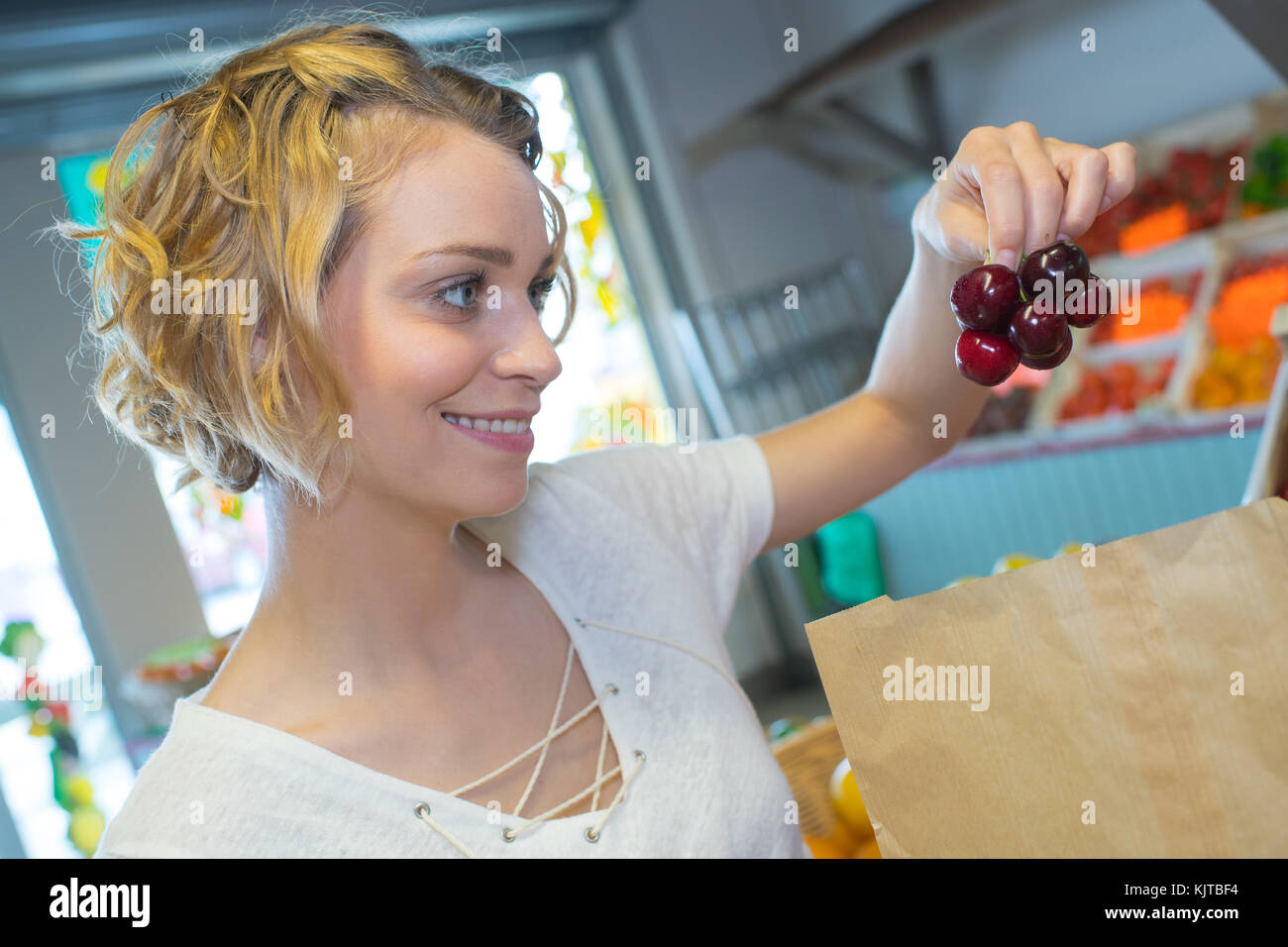 cheerful happy young woman selecting cherries at store Stock Photo - Alamy