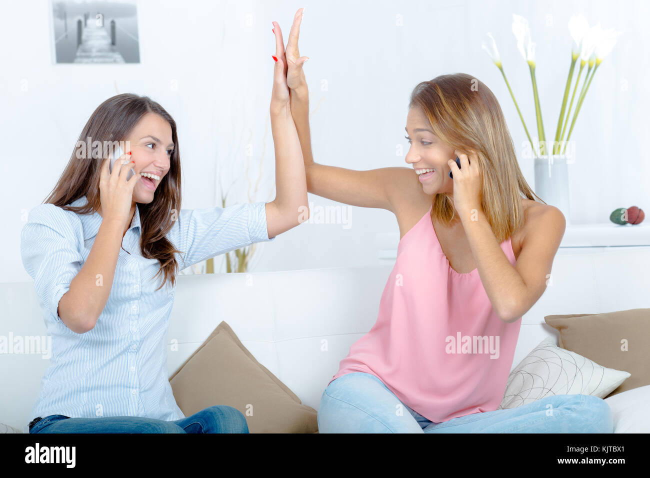 two happy women high fiving on the sofa at home Stock Photo - Alamy