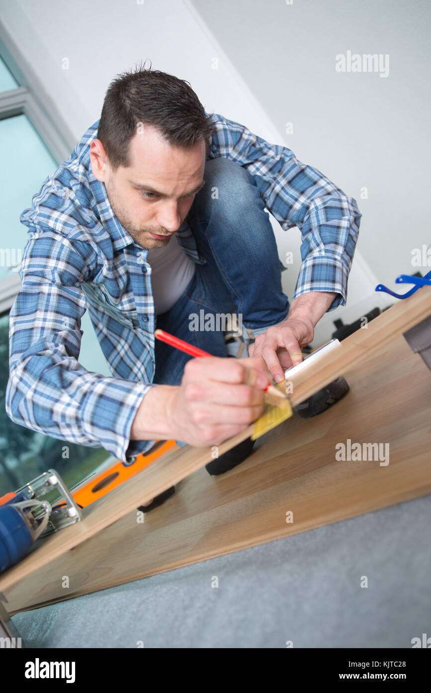 Man marking position on floorboard Stock Photo - Alamy