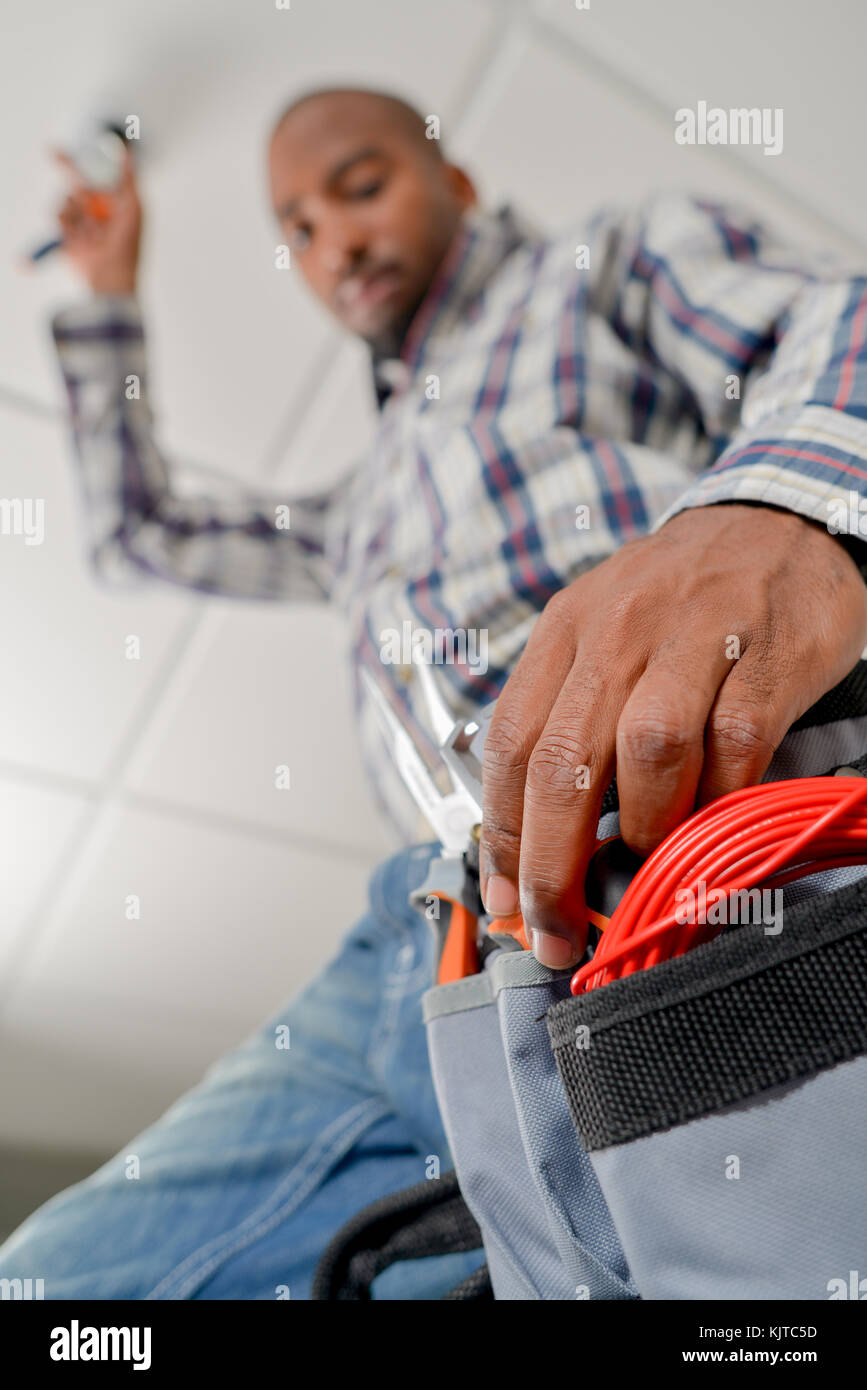 Man taking pliers from toolbelt, reaching up Stock Photo - Alamy