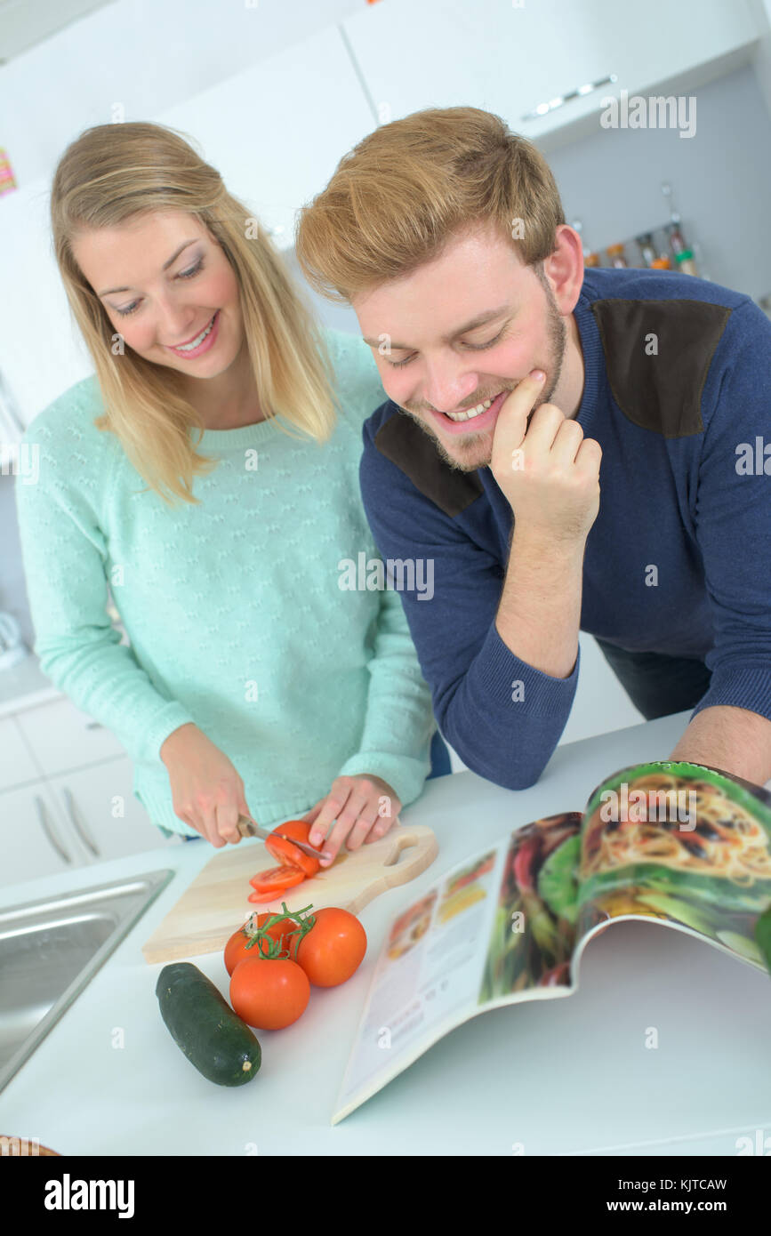 couple embracing in kitchen while checking the recipe book Stock Photo ...