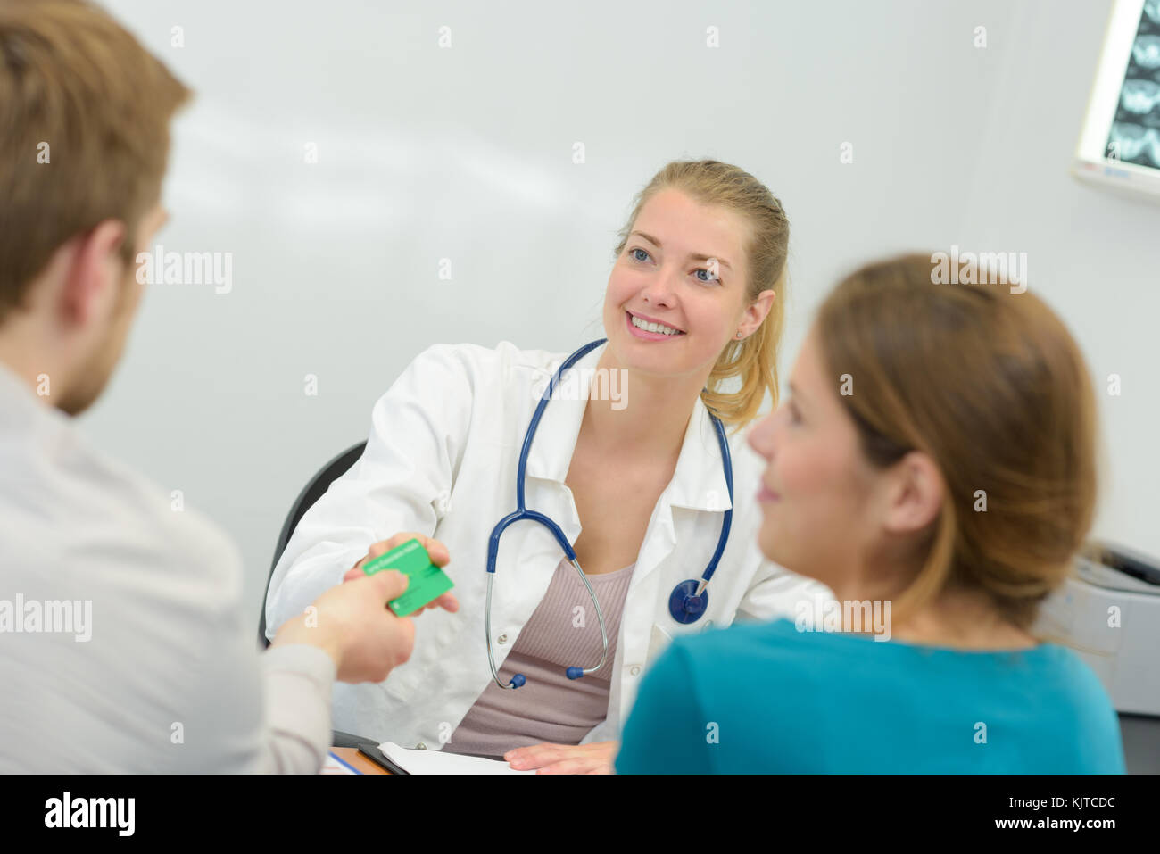 patient handing card to a young female doctor Stock Photo - Alamy
