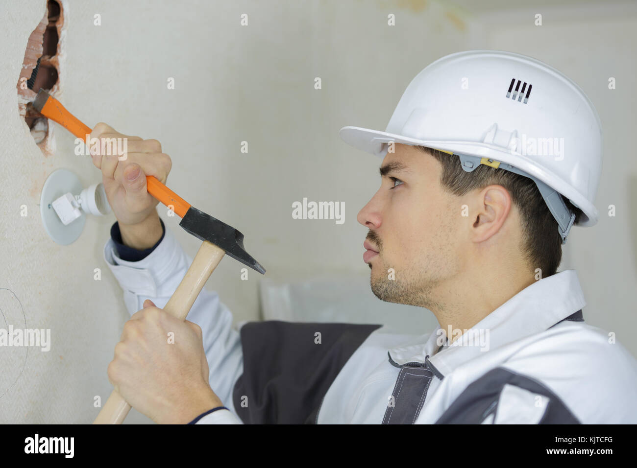 young builder with a chisel and hammer Stock Photo - Alamy