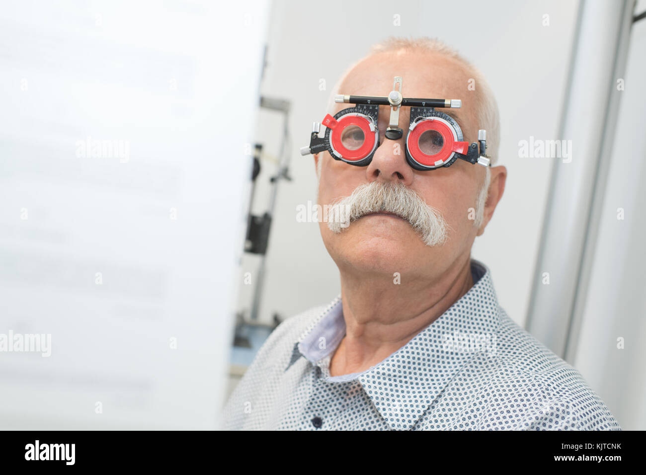 senior man wearing opticians test glasses with interchangeable lenses ...
