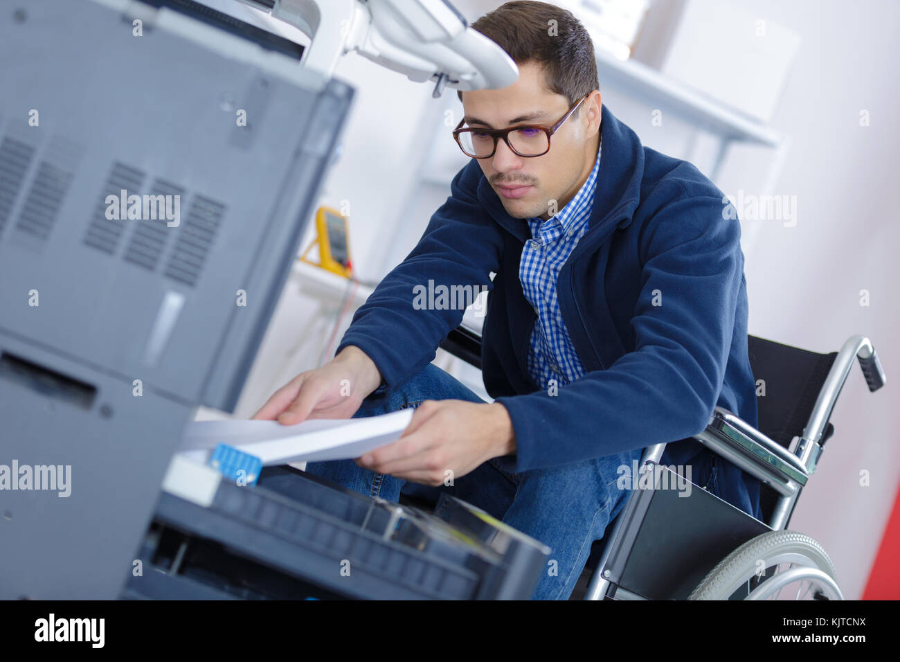 wheelchair worker putting a stack of paper into printer Stock Photo - Alamy