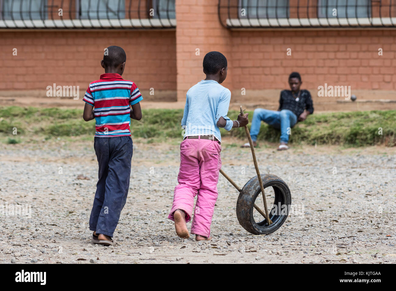 Two Malagasy boys play rolling rubber tire with two sticks. Madagascar ...