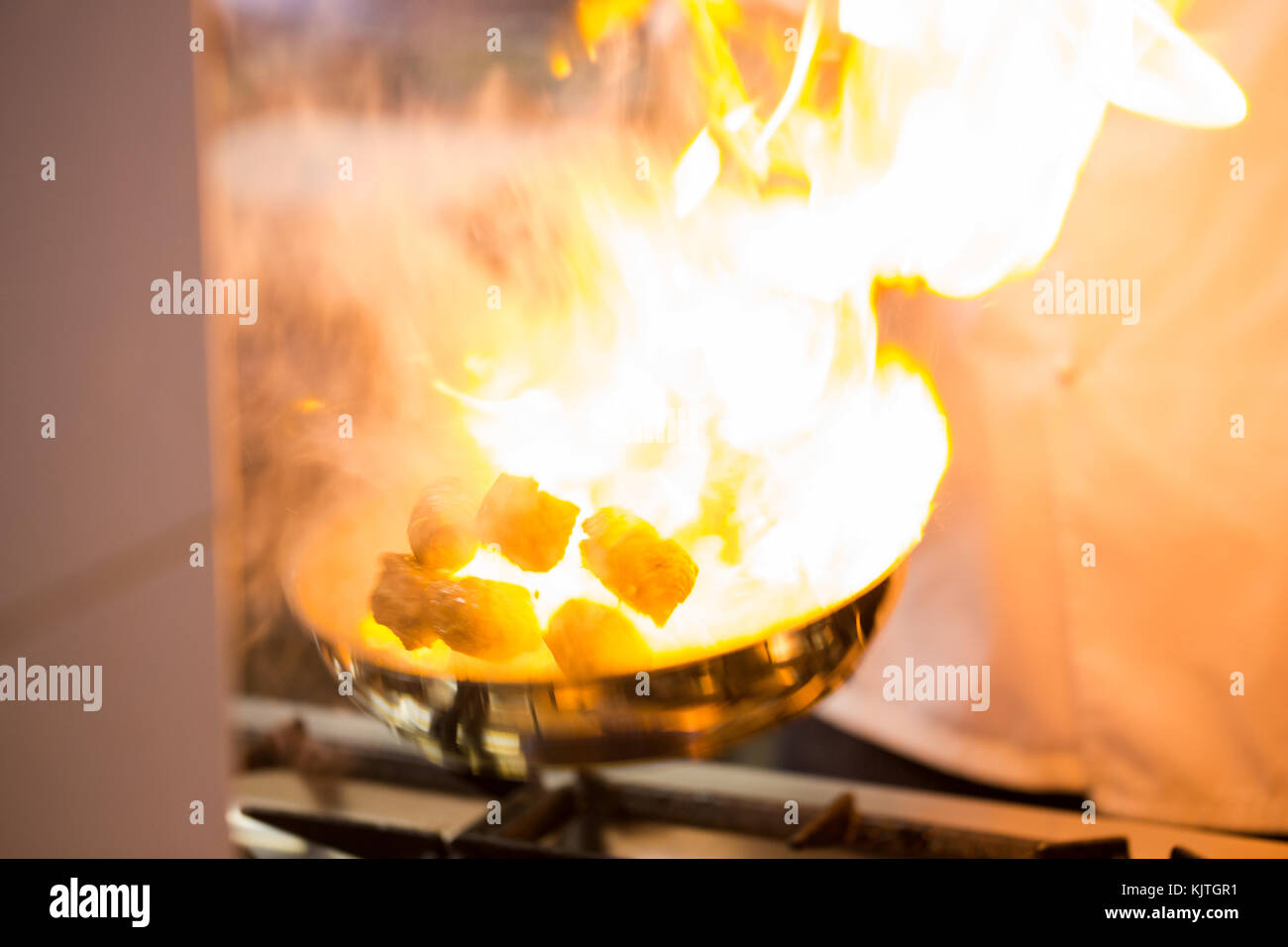 Chef cooking food in flambe style over a gas stove. Natural light and ...