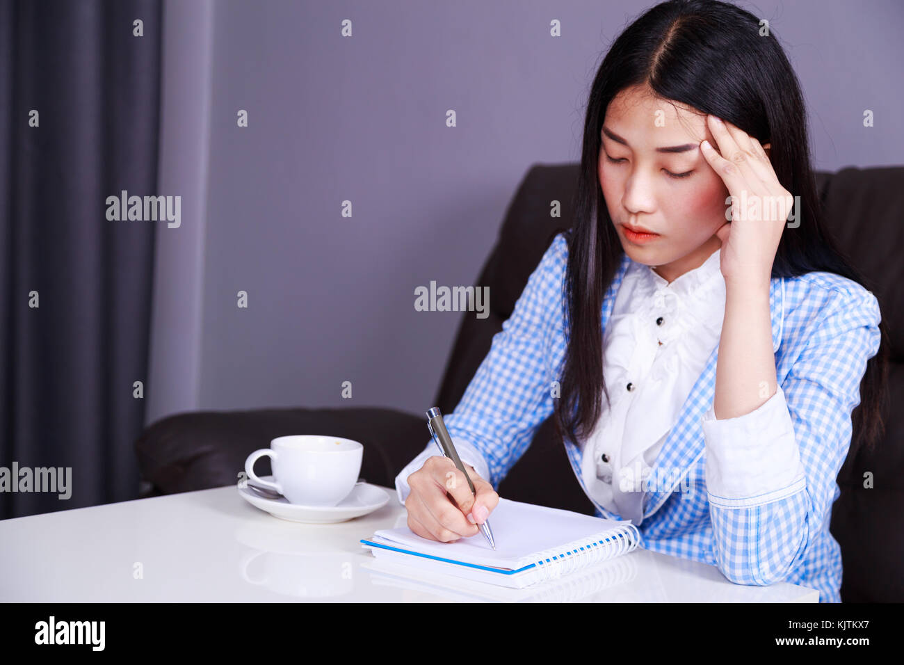 stressed young business woman sitting at her desk and writes a note on ...